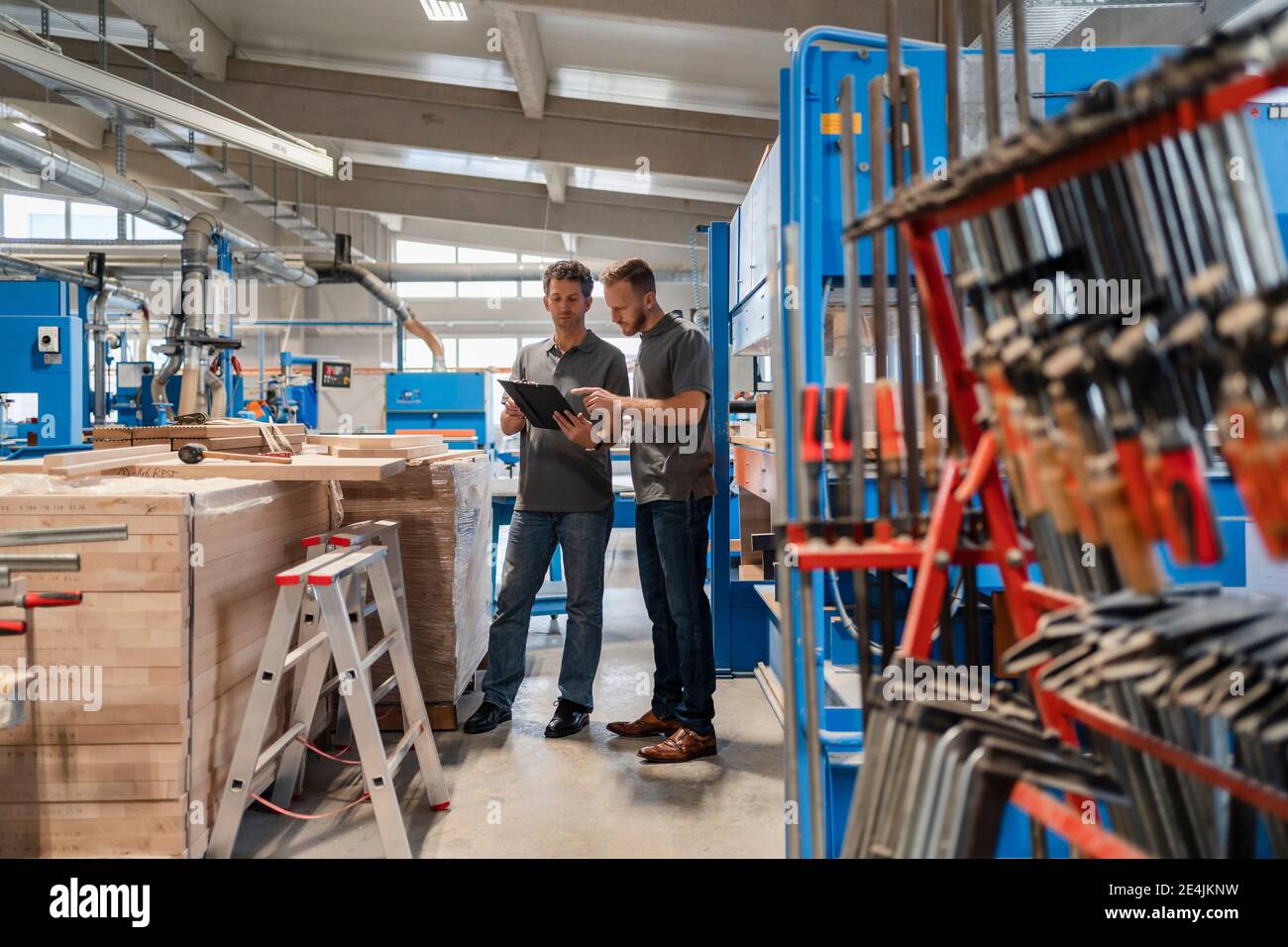 Two carpenters standing and talking in production hall Stock Photo - Alamy