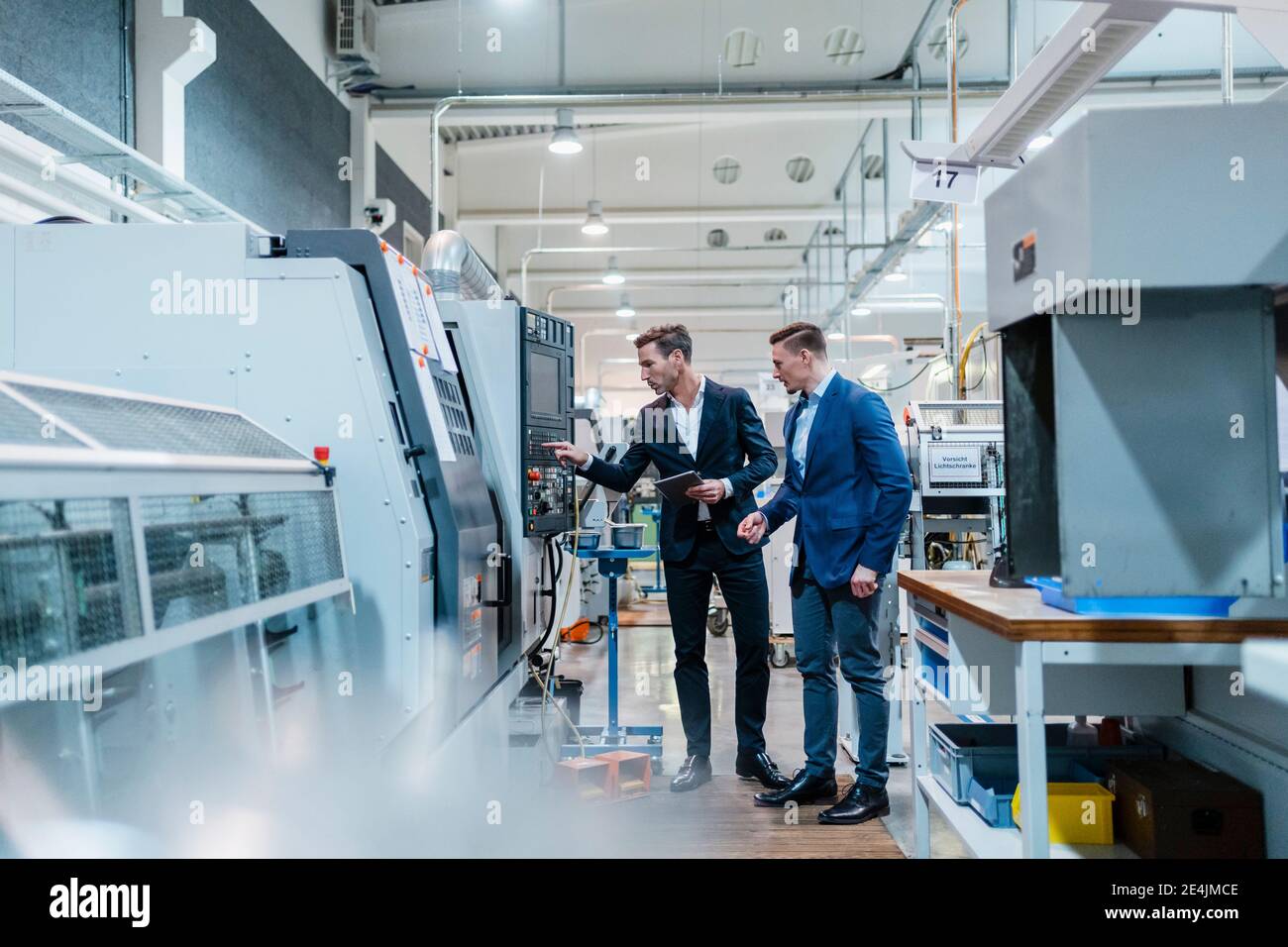 Male professionals operating manufacturing equipment in industry Stock ...