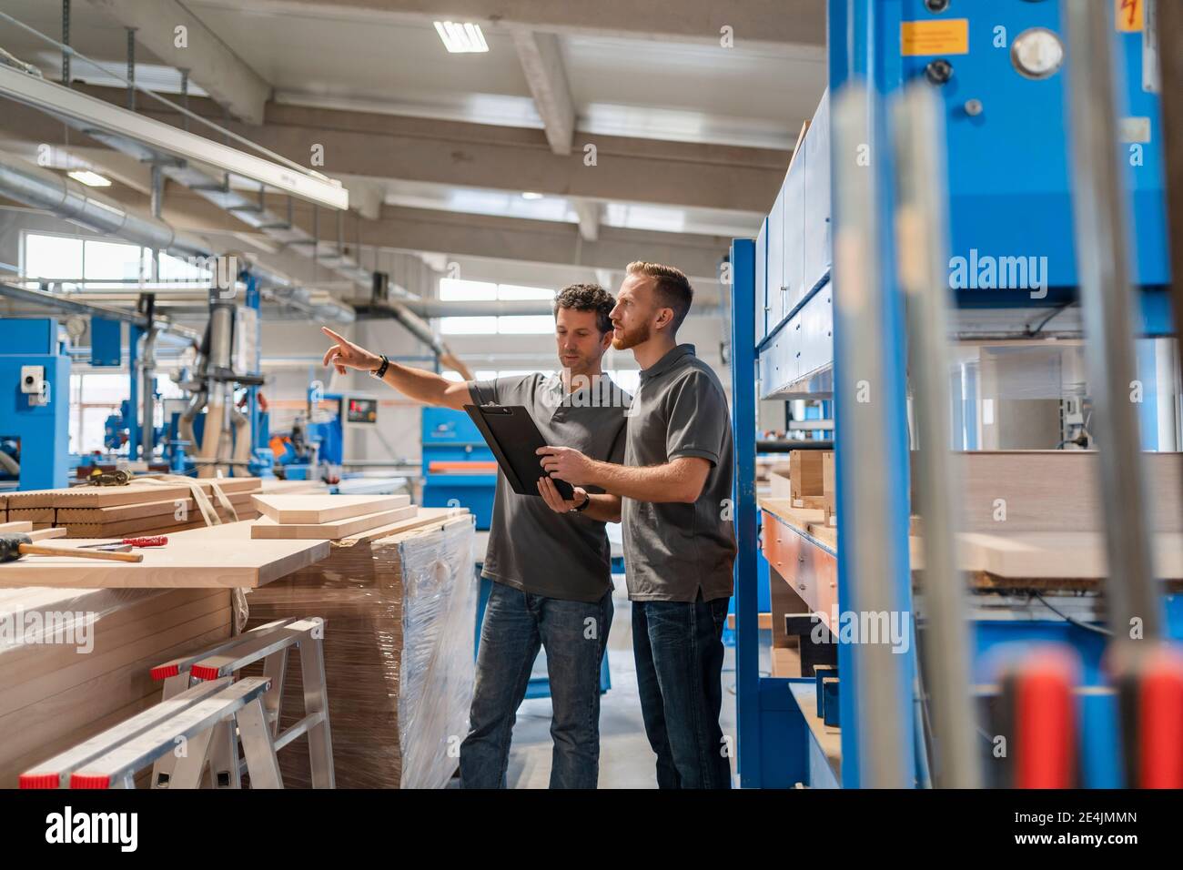 Two carpenters standing and talking in production hall Stock Photo - Alamy