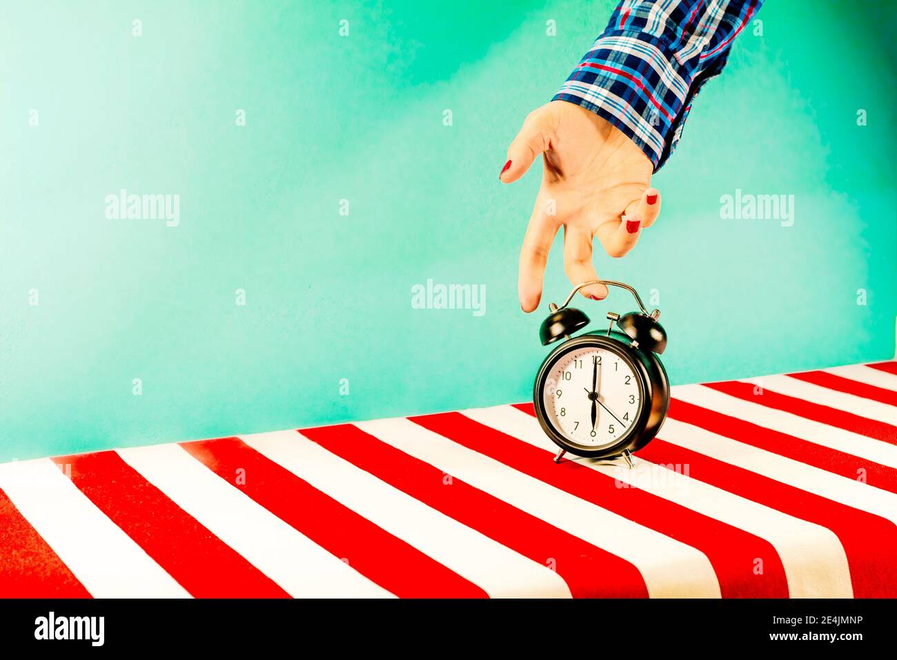 Hand of woman picking up old-fashioned alarm clock Stock Photo - Alamy