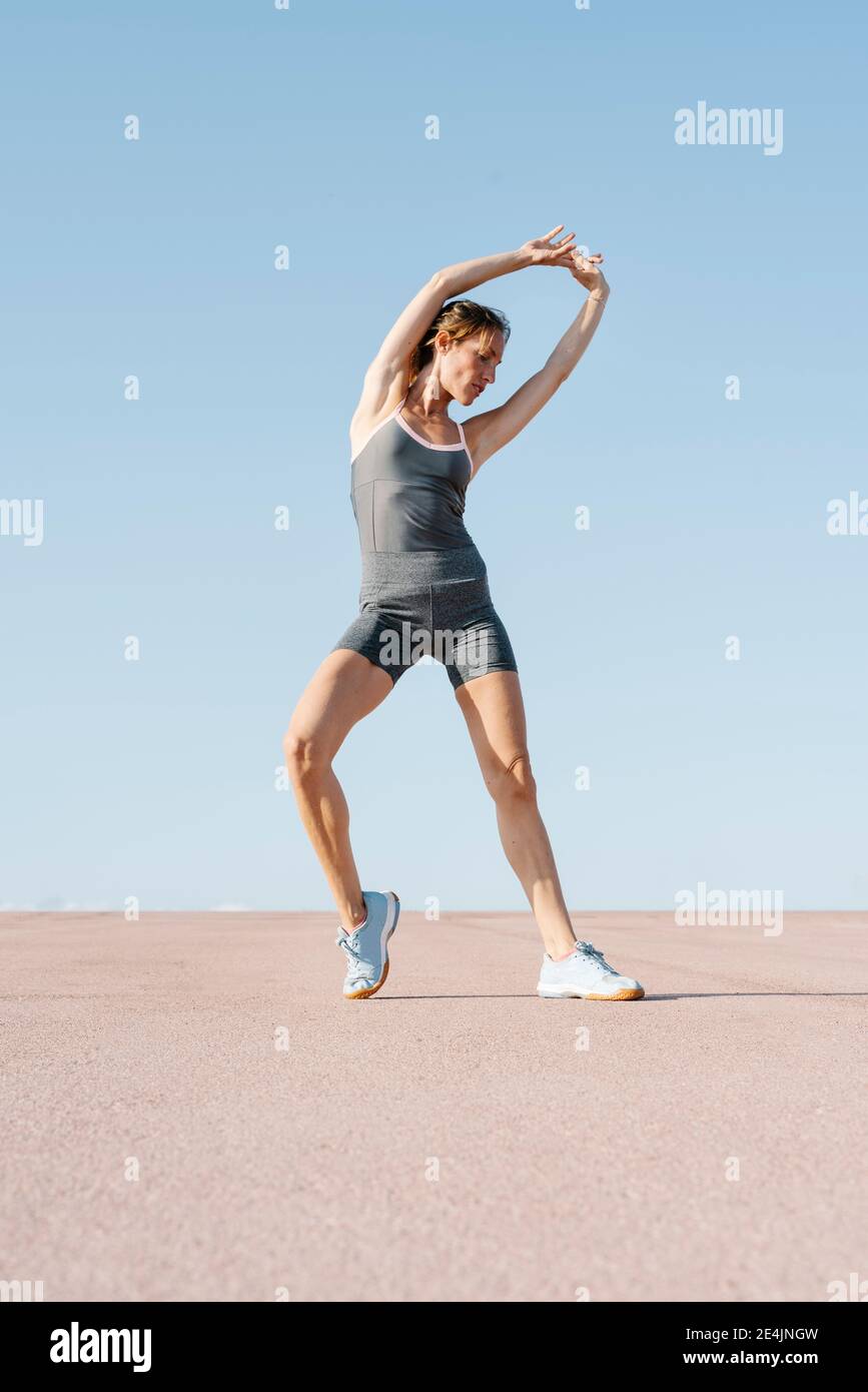 Mid adult woman strectching with hand raised Stock Photo - Alamy