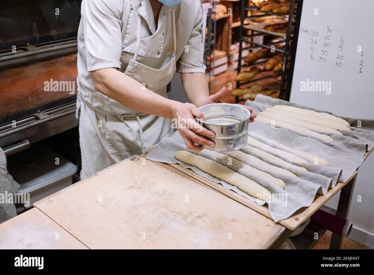 Male chef sifting flour from sieve on dough in bakery Stock Photo - Alamy