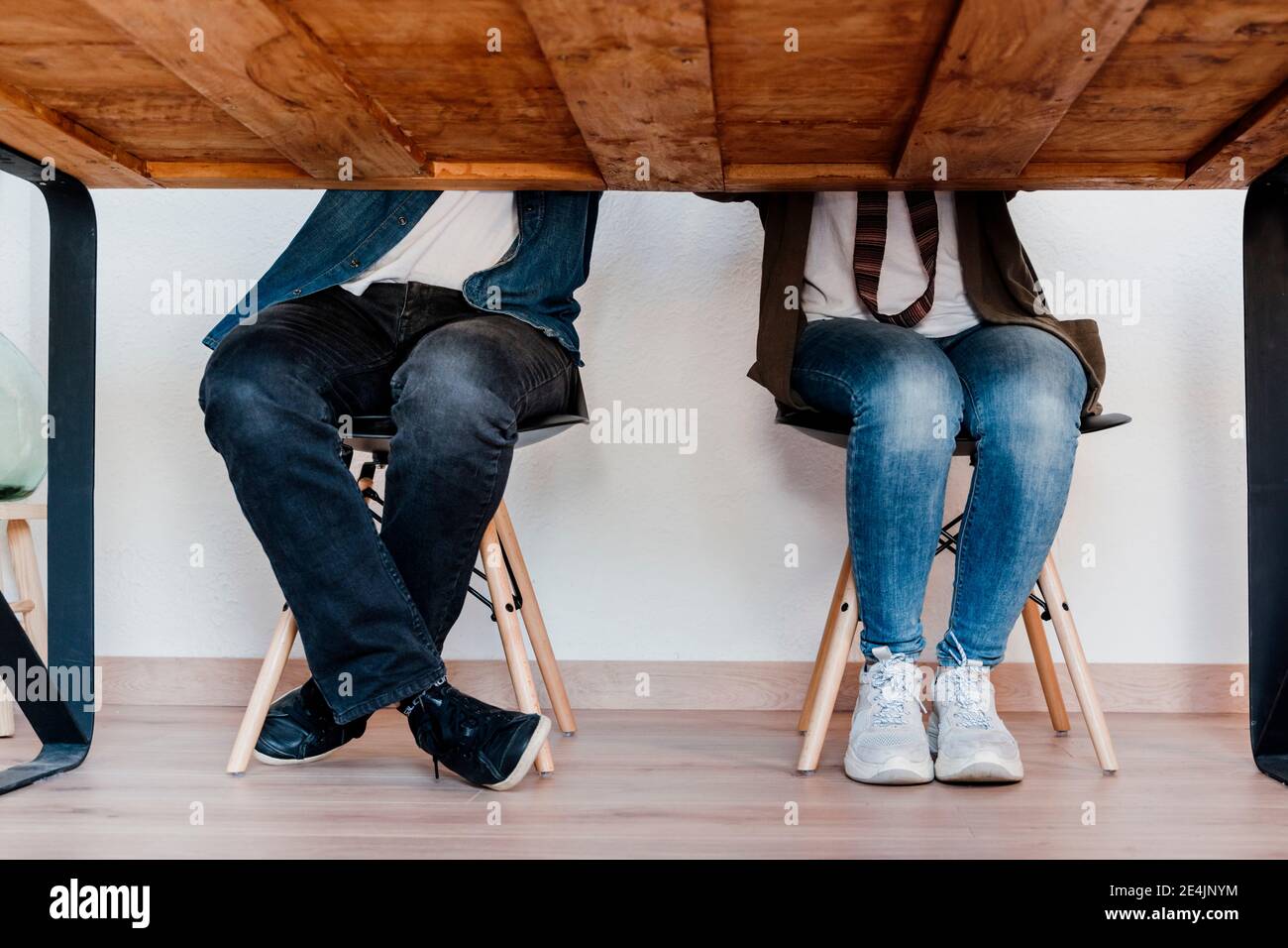 Male and female colleagues in casuals sitting on stool at home office ...