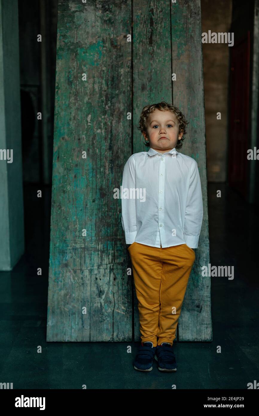 Sad boy standing with hands in pockets Stock Photo - Alamy