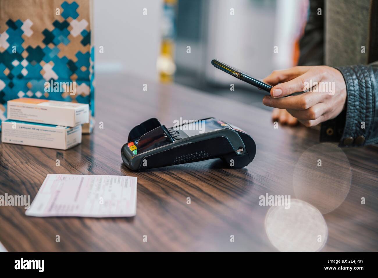 Hand of customer with smart phone at checkout counter in chemist shop ...