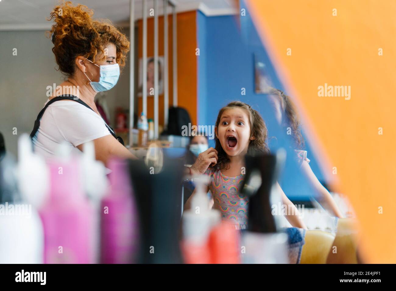 Shocked girl shouting at female hairdresser seen from mirror reflection ...