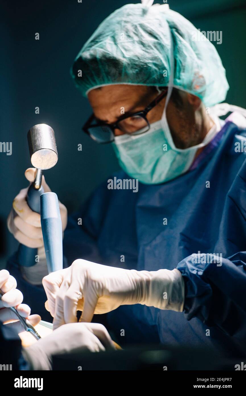Male orthopedic surgeons using medical equipment for ankle surgery in ...