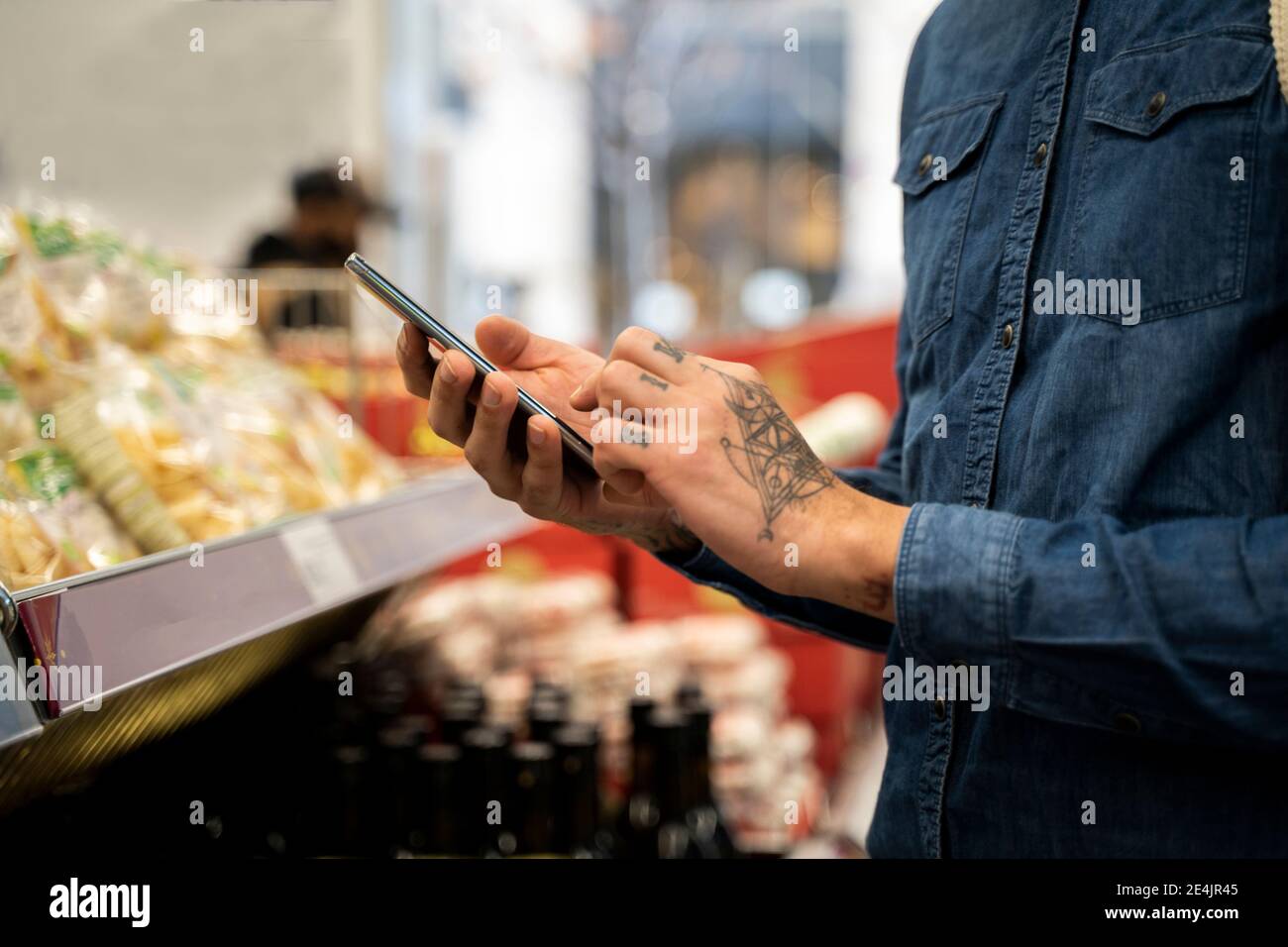 Hand holding smartphone in supermarket hi-res stock photography and ...