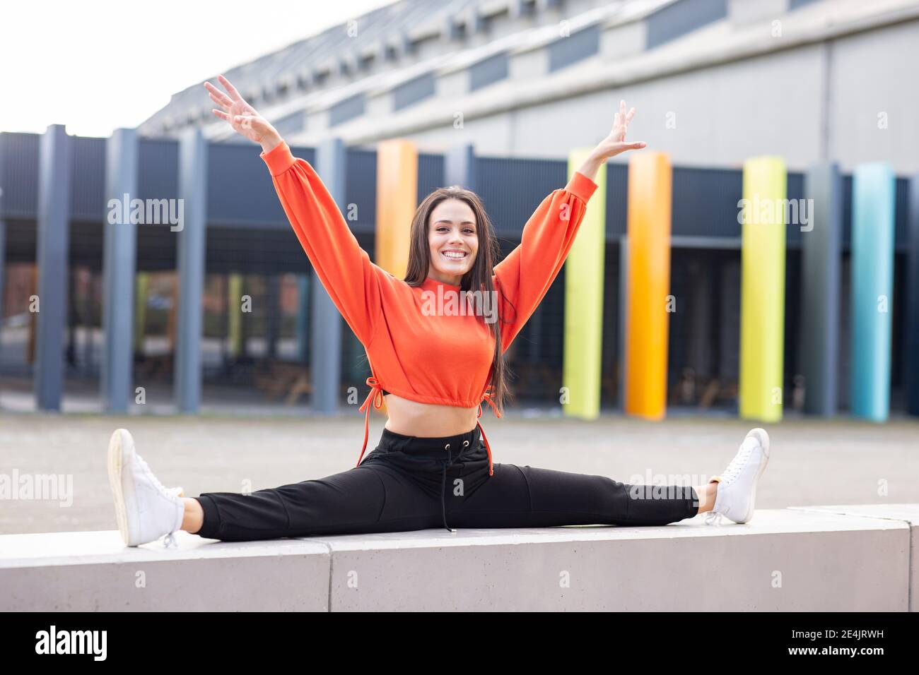Portrait of beautiful brunette doing splits in front of colorful ...