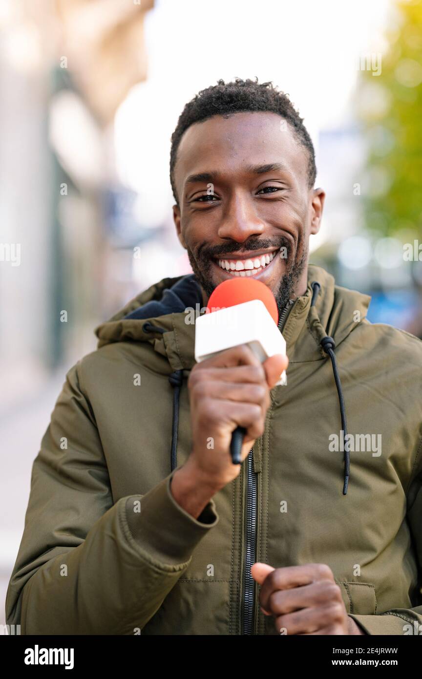 Close-up of smiling male presenter talking over microphone Stock Photo ...