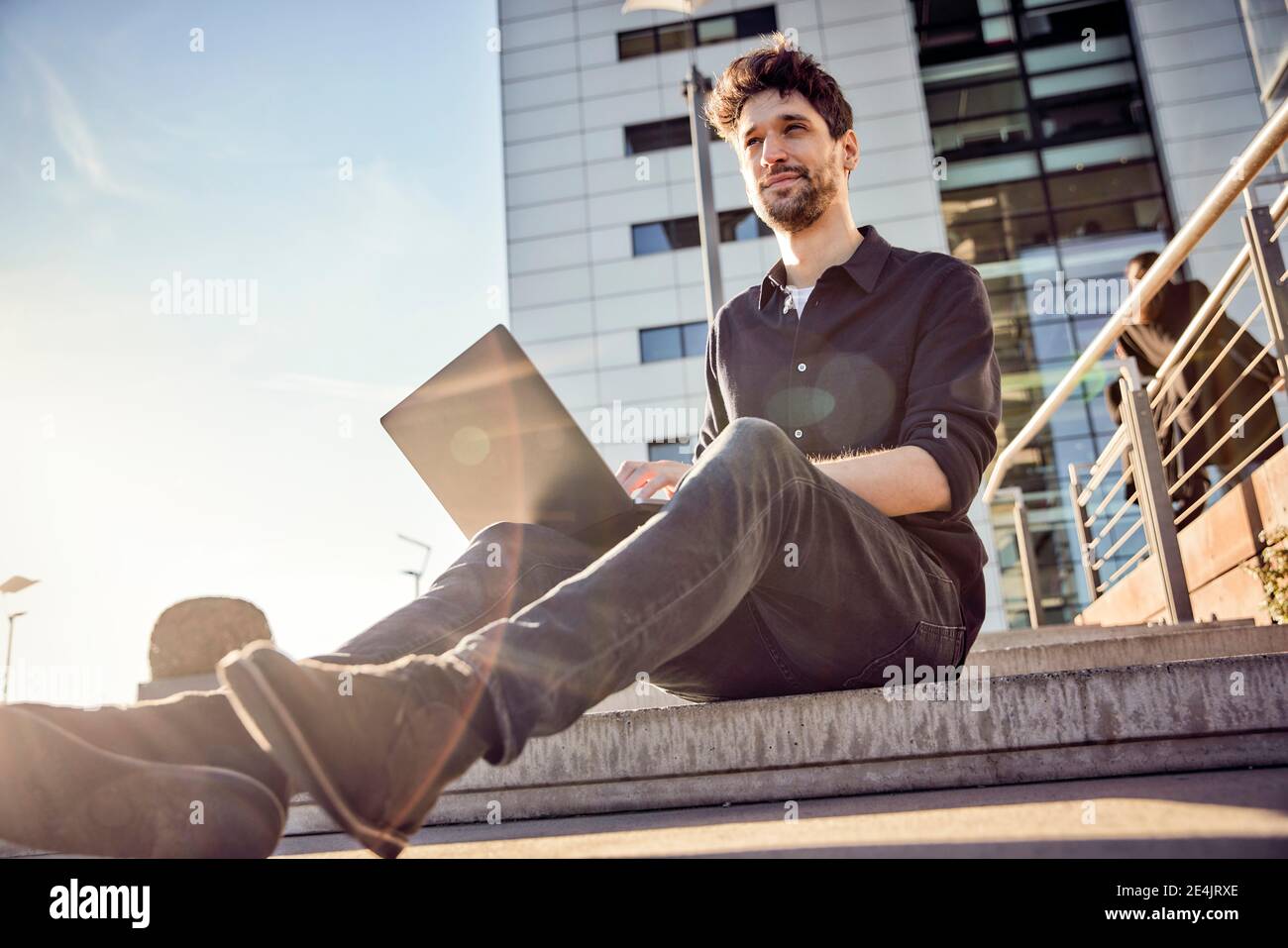 Entrepreneur using laptop while sitting on steps Stock Photo - Alamy