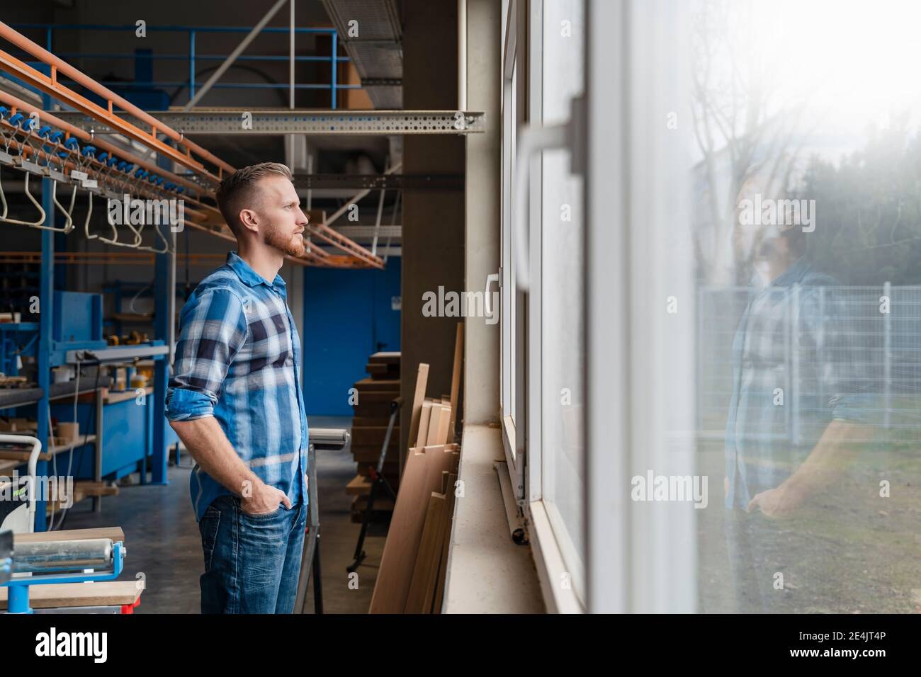 Portrait of carpenter looking through window in production hall Stock ...