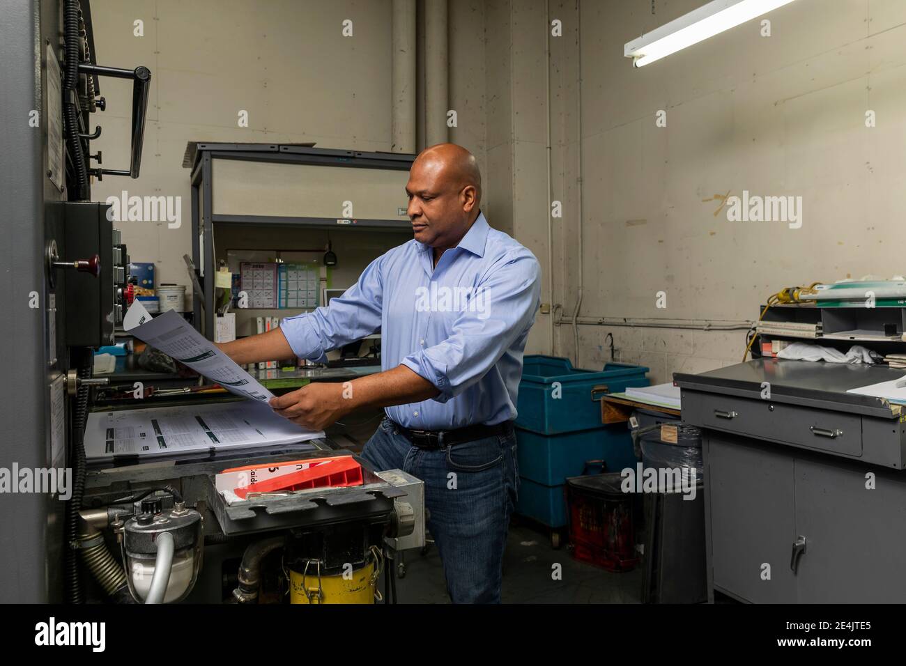 Mature supervisor checking quality of paper while standing by print ...