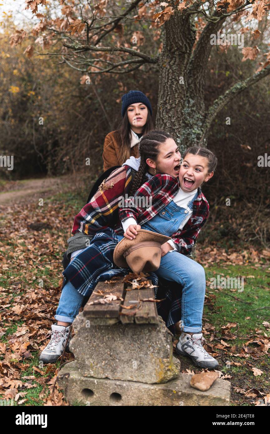 Three smiling sisters on bench in Autumn landscape Stock Photo - Alamy