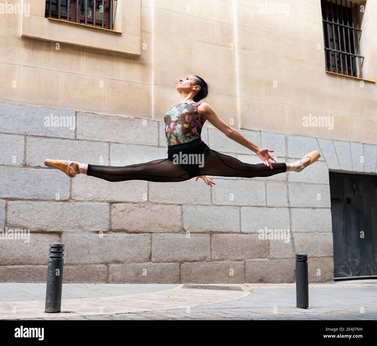 Dancer wearing leotard dancing while jumping with legs stretched on ...