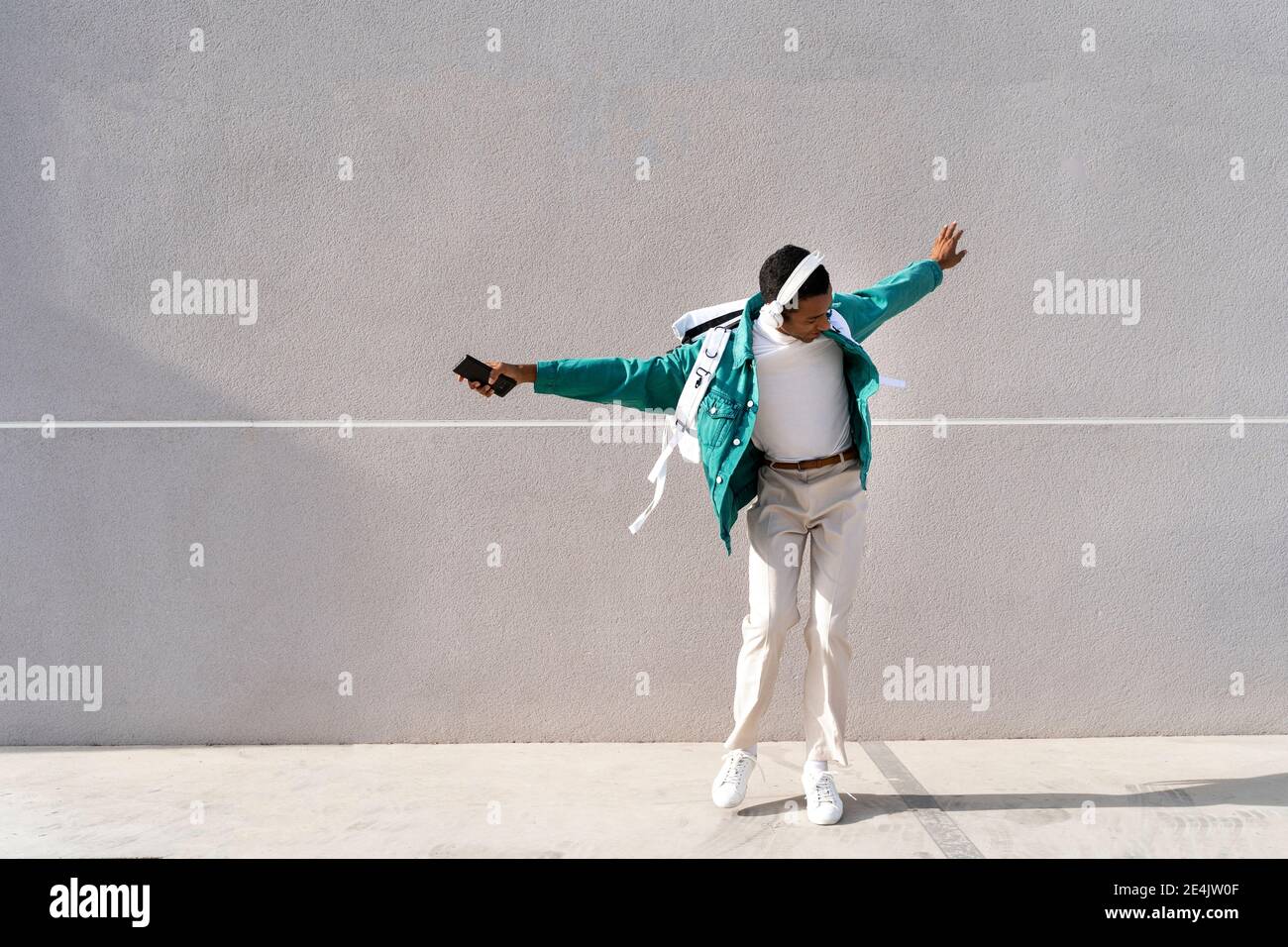 Carefree man with headphones and mobile phone dancing with arms ...