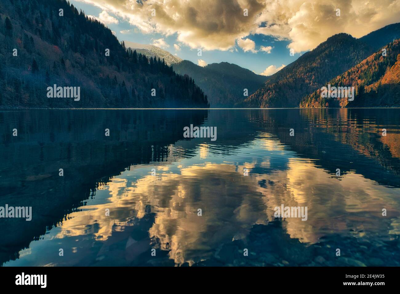 Clouds and surrounding mountains reflecting in Lake Ritsa at dusk ...
