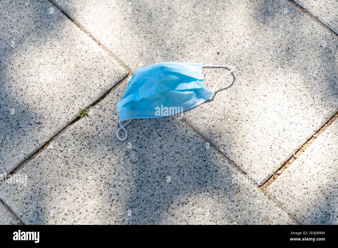 disposable blue mask on the stone path in the park. incorrect disposal ...