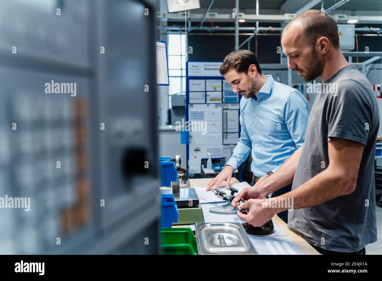 Engineers working while standing by table at industry Stock Photo - Alamy