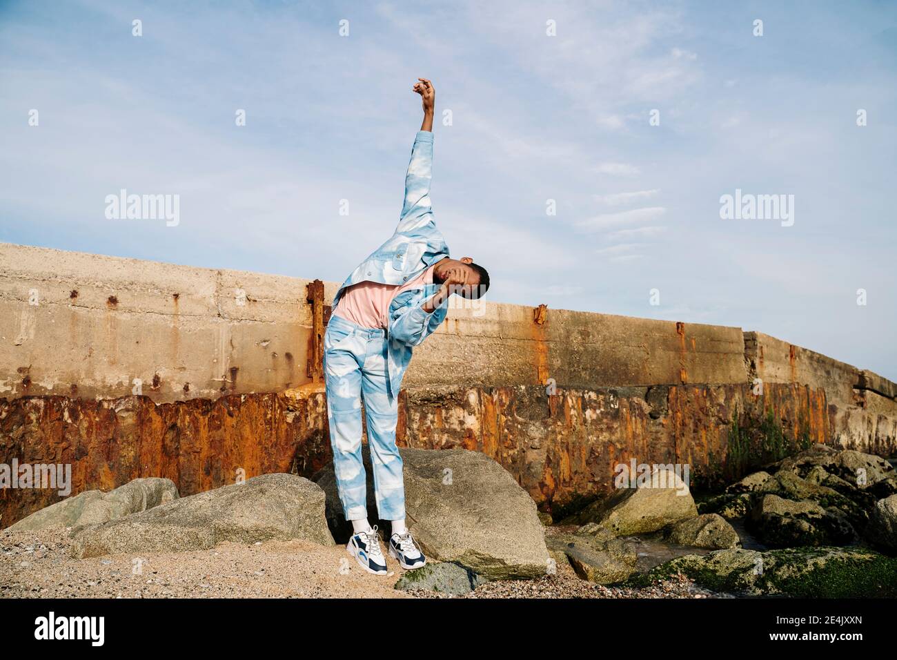 Man covering eyes and raising hand while bending against sky Stock ...