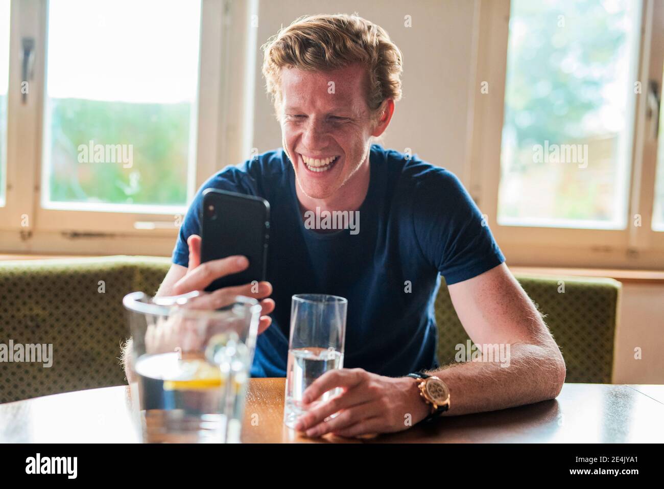 Man laughing while on video call through smart phone in living room ...