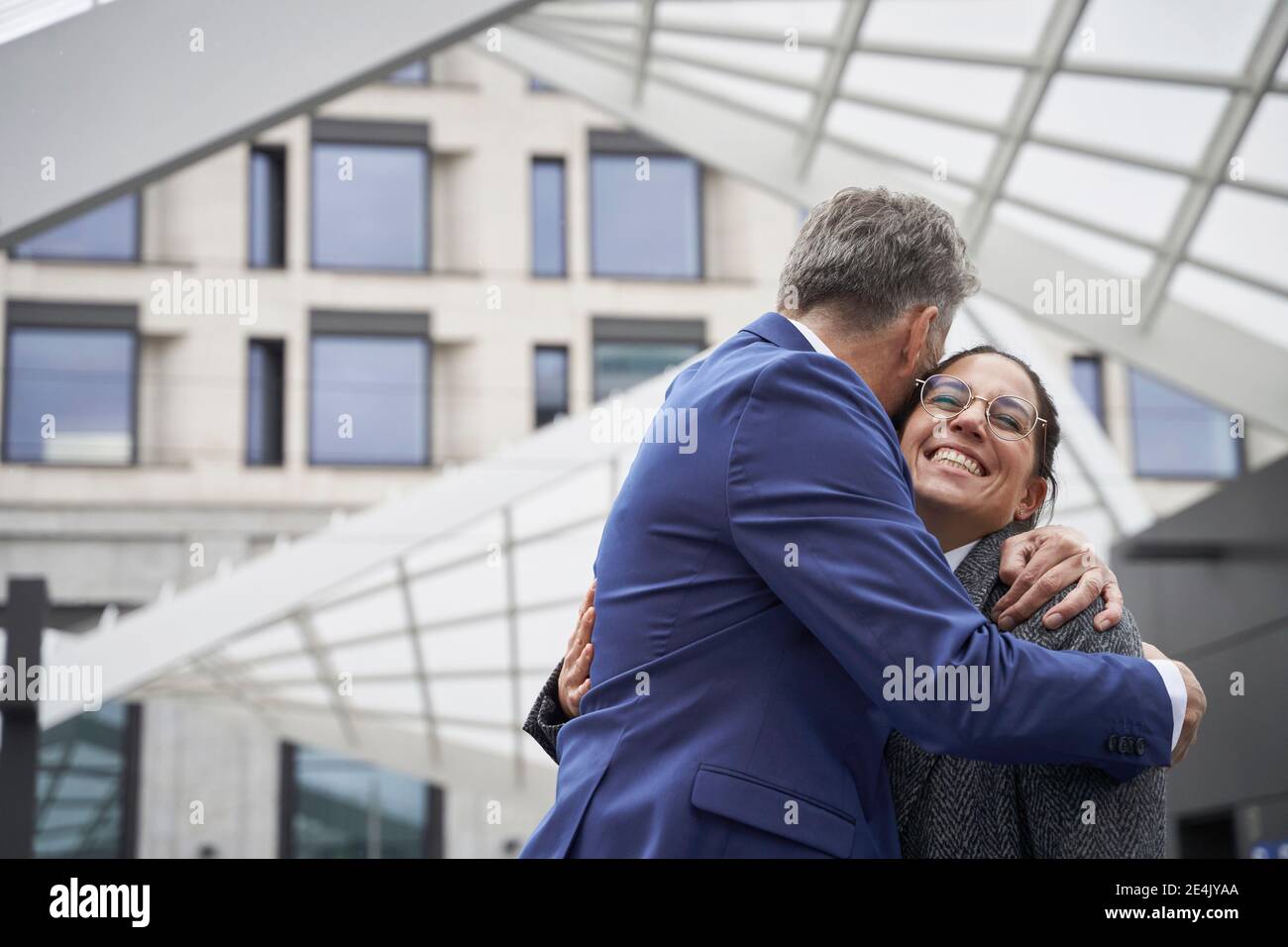 Senior businessman hugging cheerful businesswoman while greeting in ...