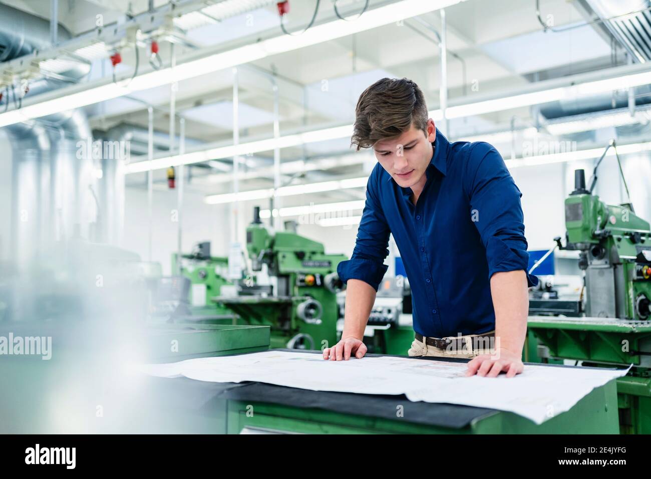Male entrepreneur looking over floor plan while working on desk in ...