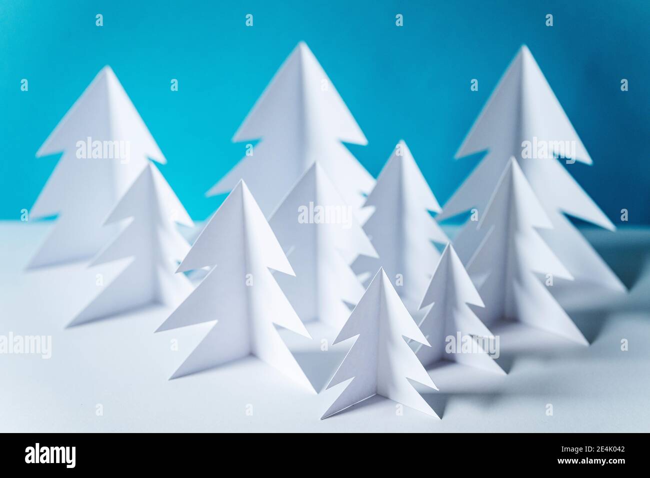 Paper forest with white trees on table against blue background Stock ...