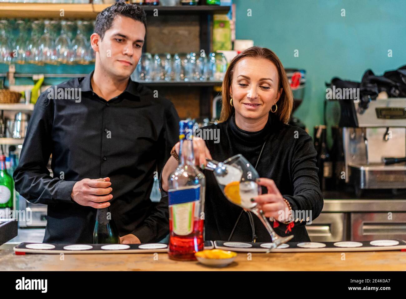 Female bartender preparing cocktail with male assistant Stock Photo - Alamy