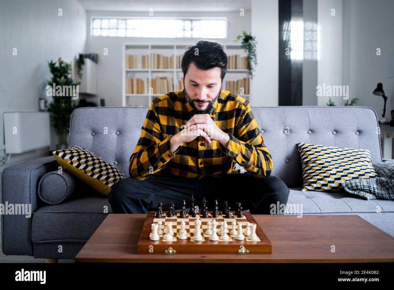 Man sitting on sofa in front of chess board Stock Photo - Alamy