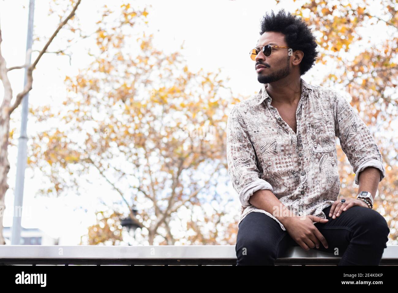 Stylish mid adult man with afro hair wearing sunglasses sitting on ...