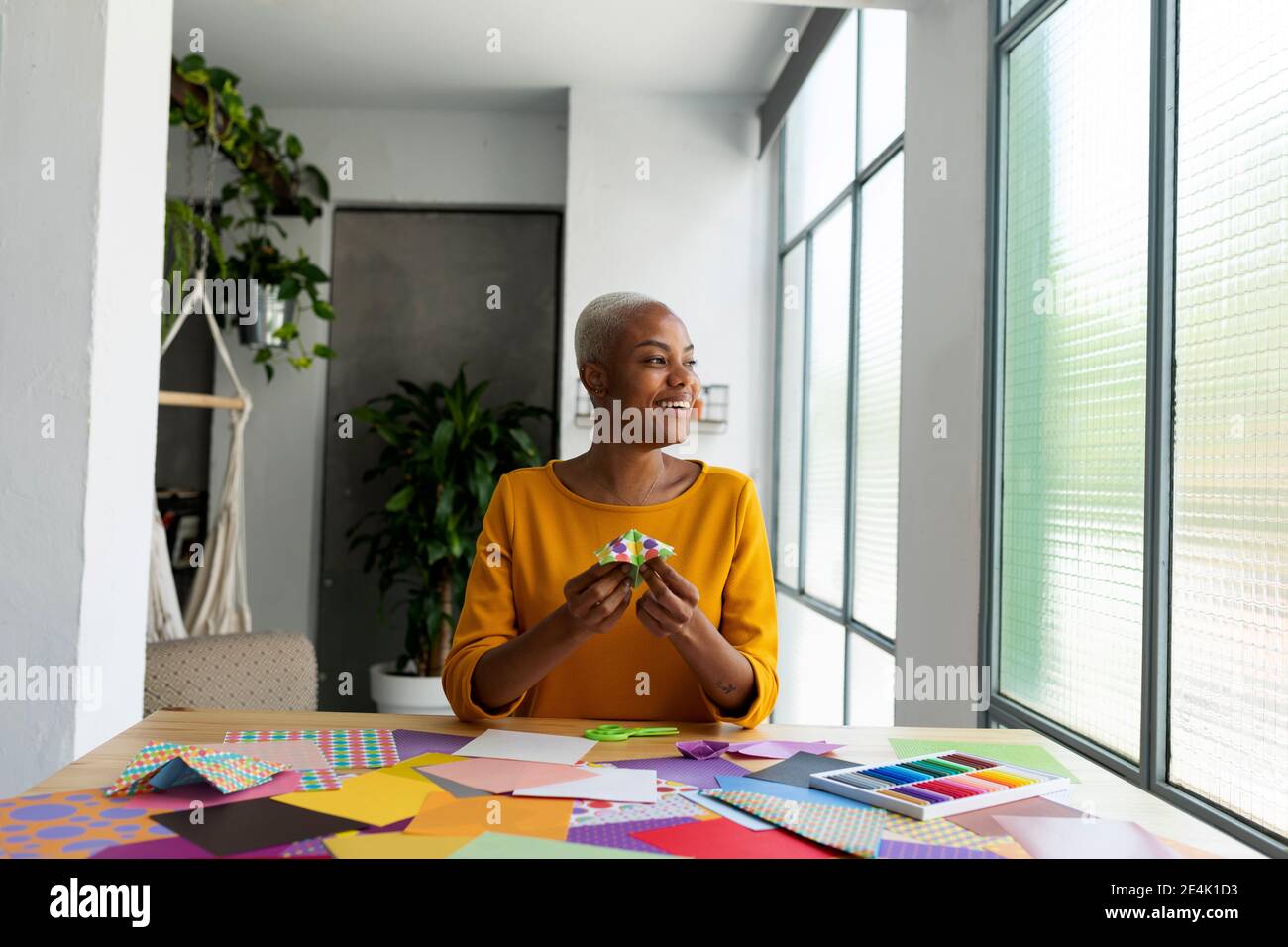 Origami artist sitting in studio working with colorful paper Stock ...