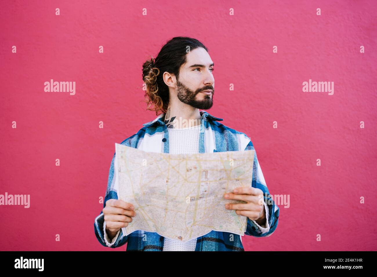 Man holding map while standing against red wall Stock Photo - Alamy