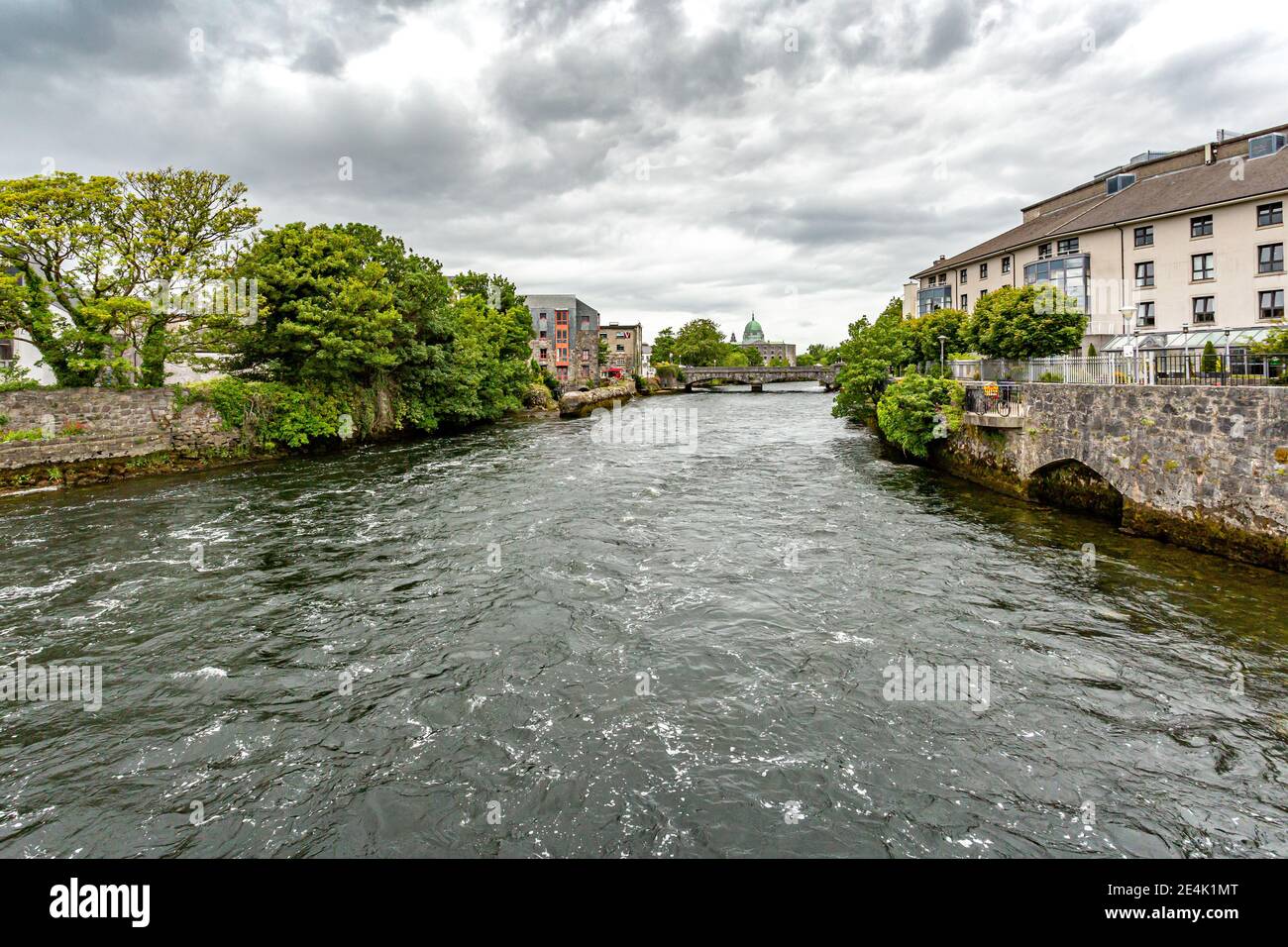 River Corrib between stone walls and green vegetation with the William ...