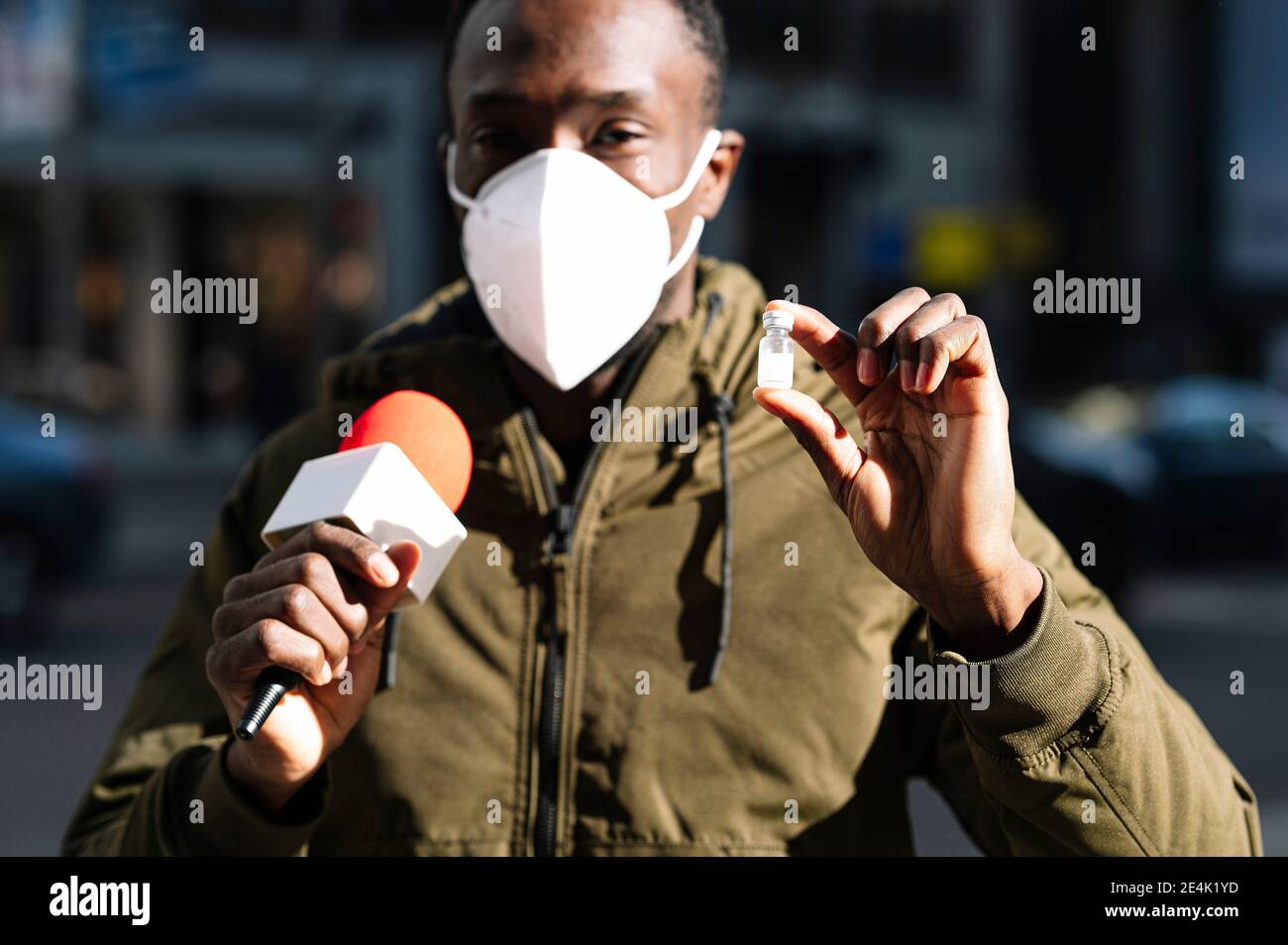 Close-up of male reporter wearing face mask showing vaccine while ...