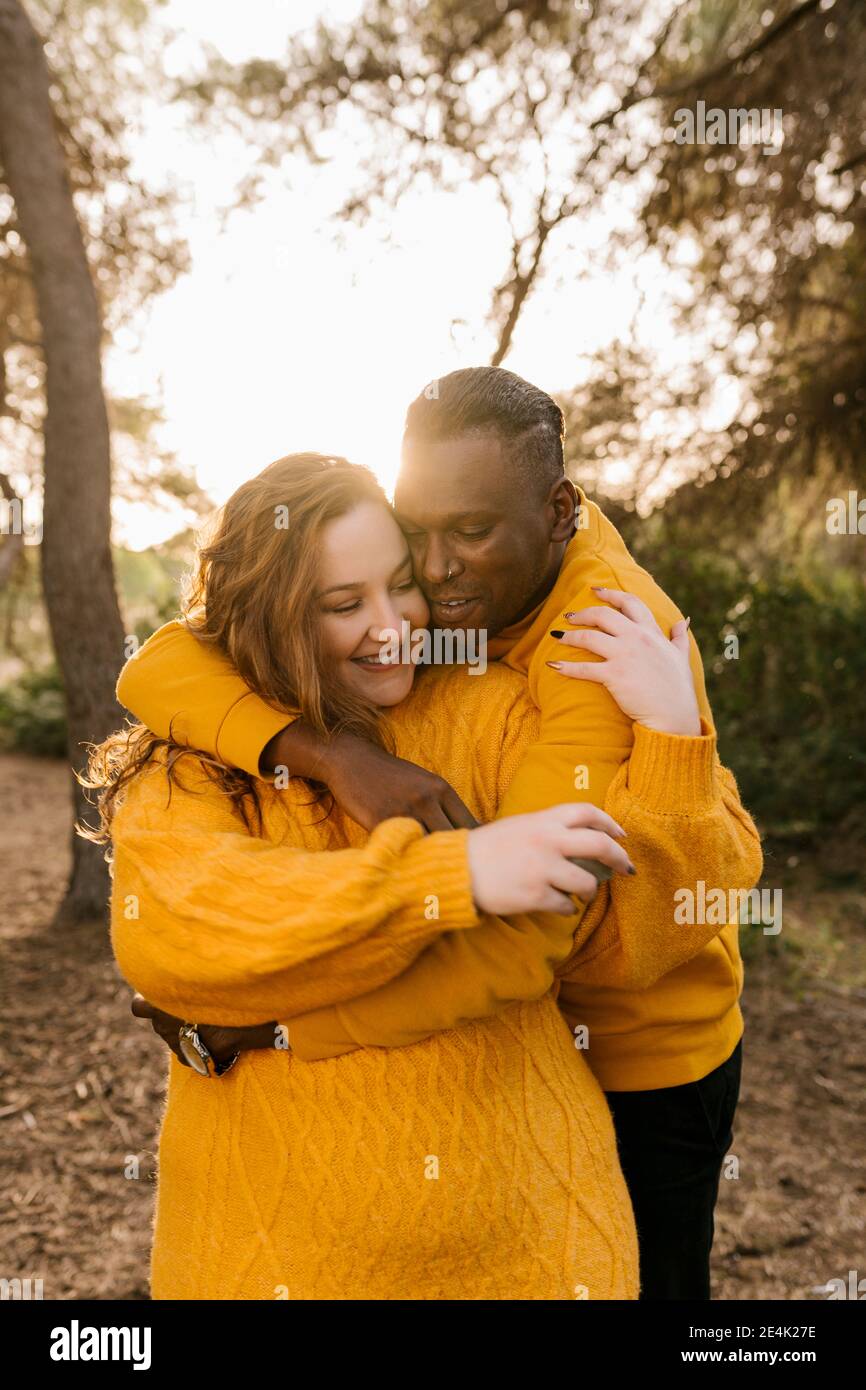 Happy boyfriend hugging girlfriend while standing at forest Stock Photo ...