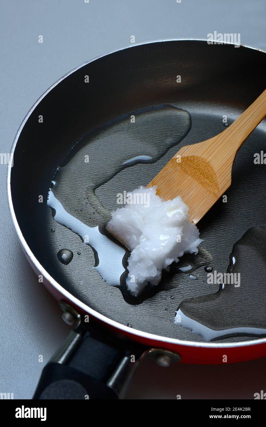 Coconut oil with bamboo spatula in frying pan Stock Photo - Alamy