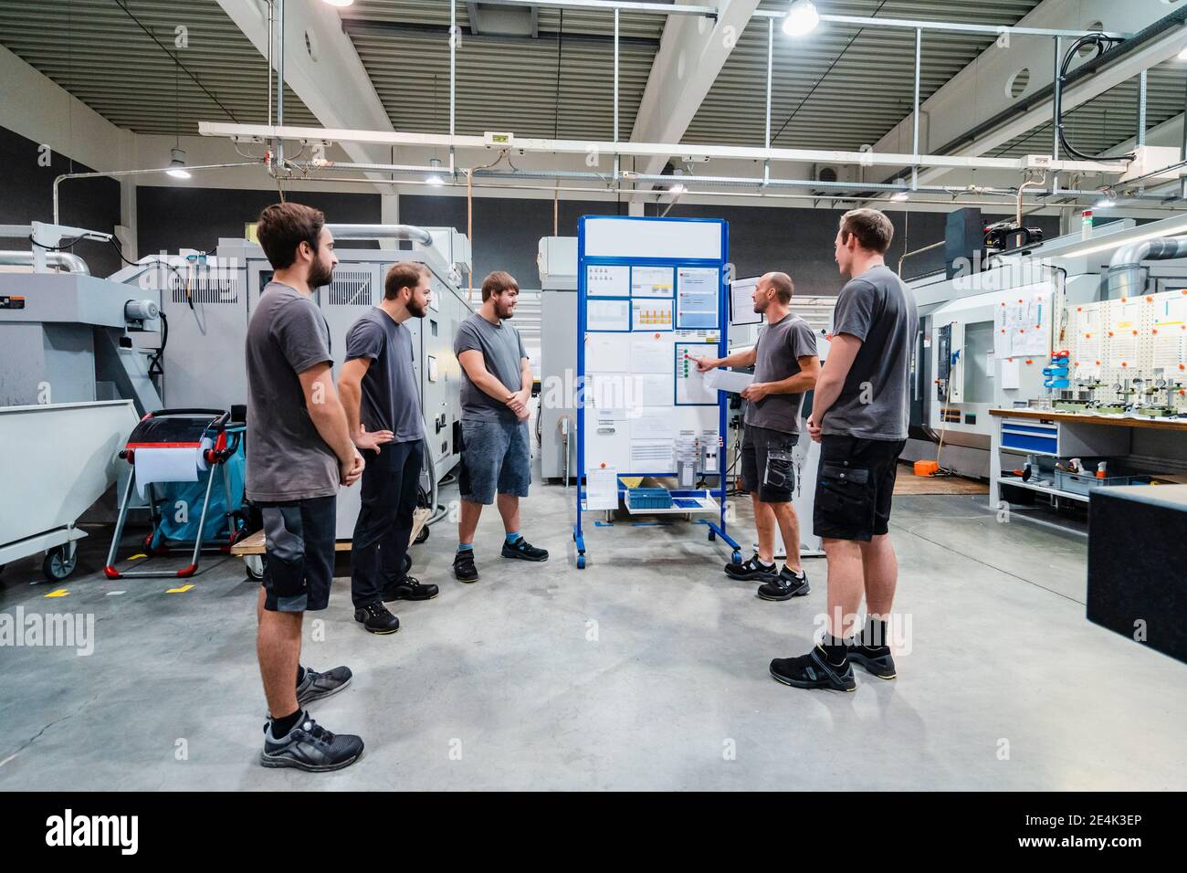 Maintenance engineers planning over chart on whiteboard while standing ...