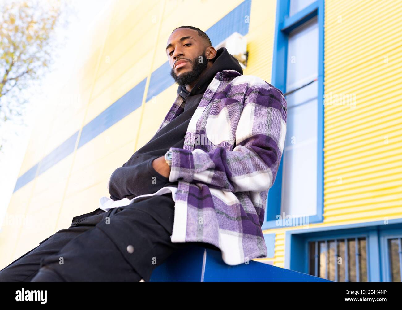 Male rapper with hands in pockets against building exterior Stock Photo ...