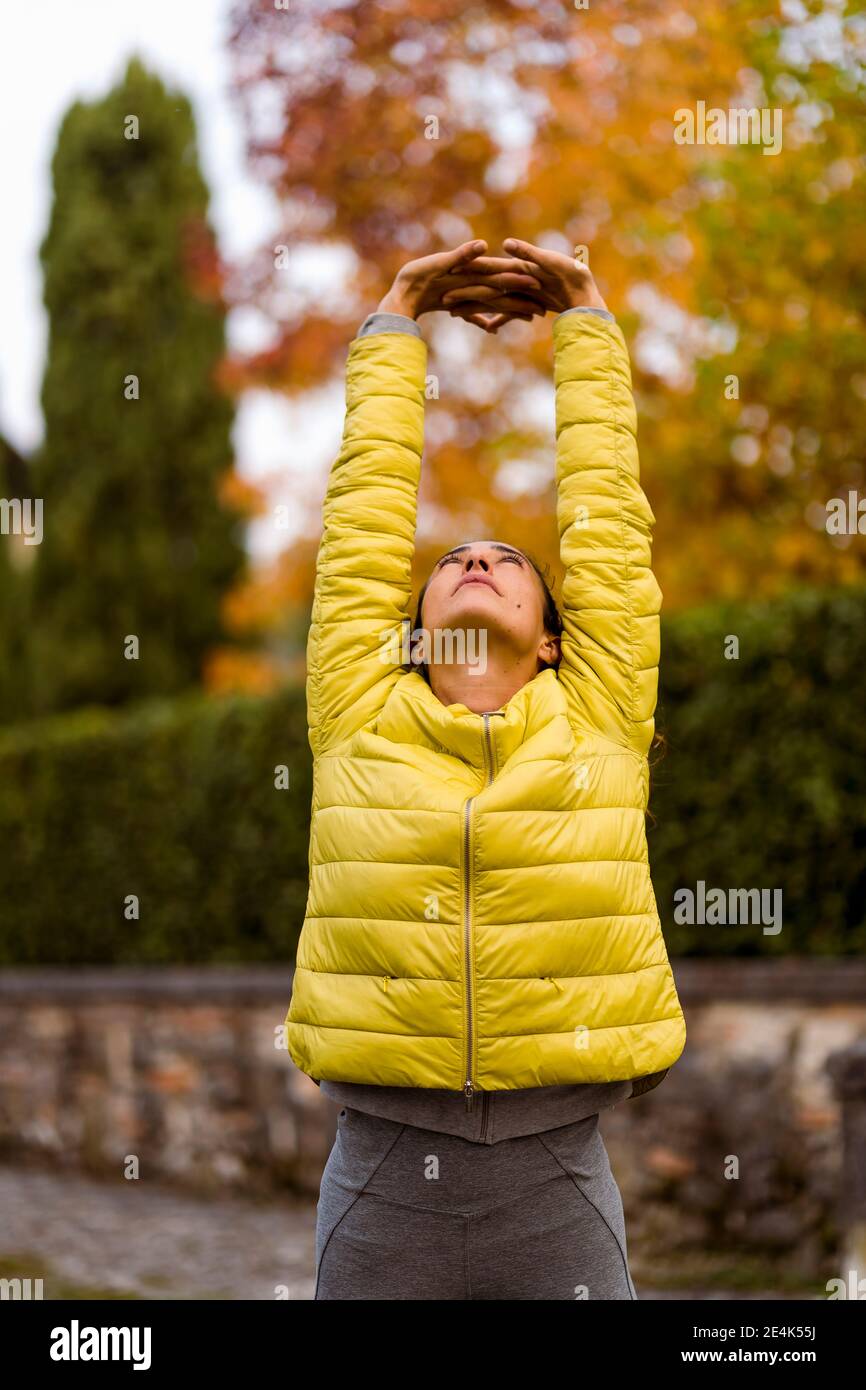 Sportswoman with hand raised stretching while exercising at park Stock ...