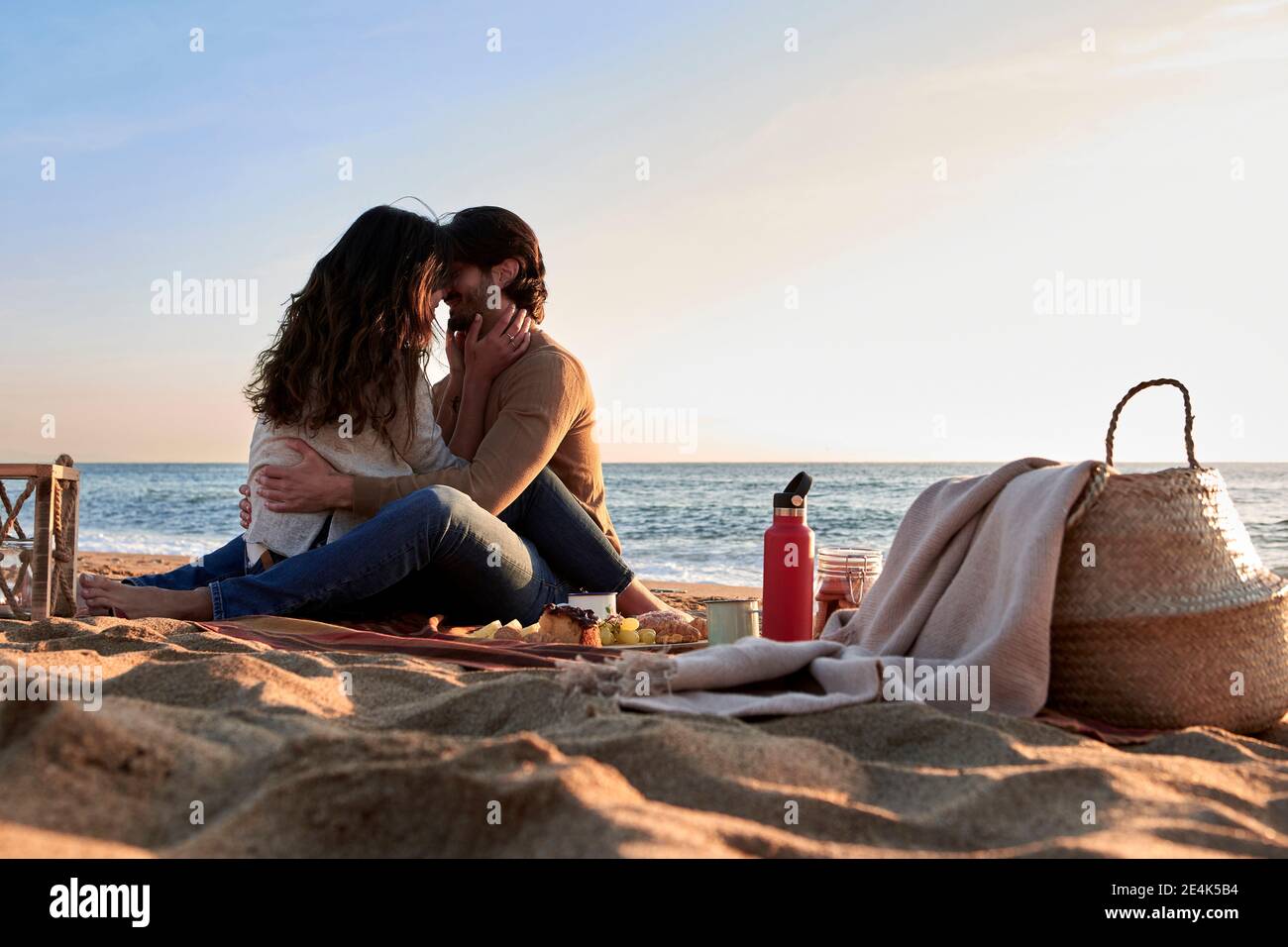 Girlfriend and boyfriend romancing while sitting face to face on beach ...