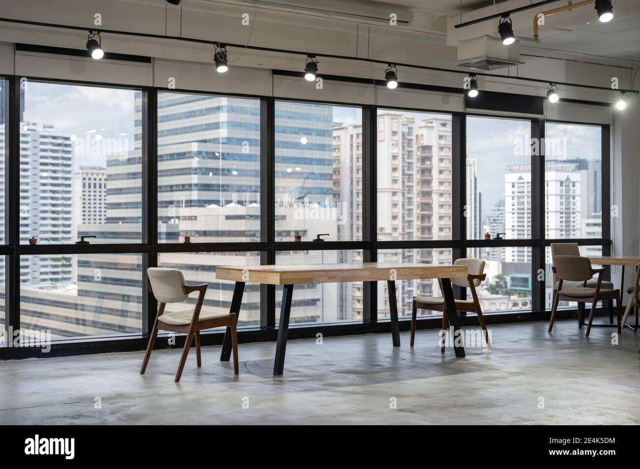 Empty wooden conference table with chairs in coworking space on ...