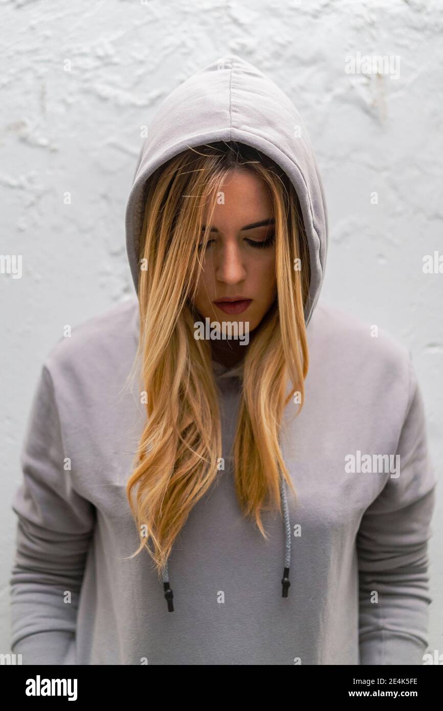 Close-up of sad woman with eyes closed wearing hood while standing ...