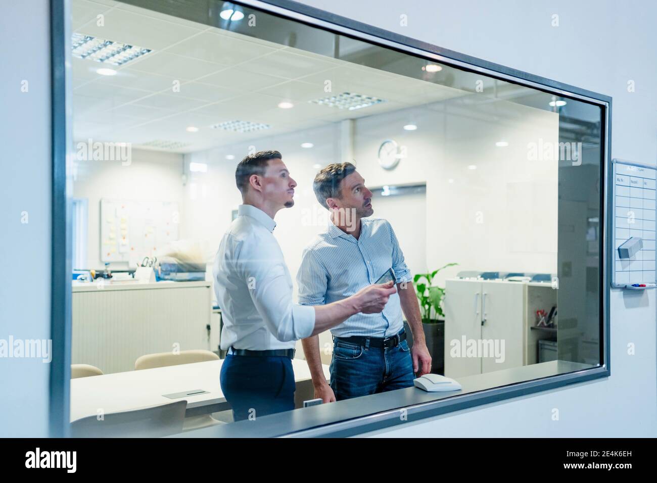 Businessman with male coworker looking through glass window while ...