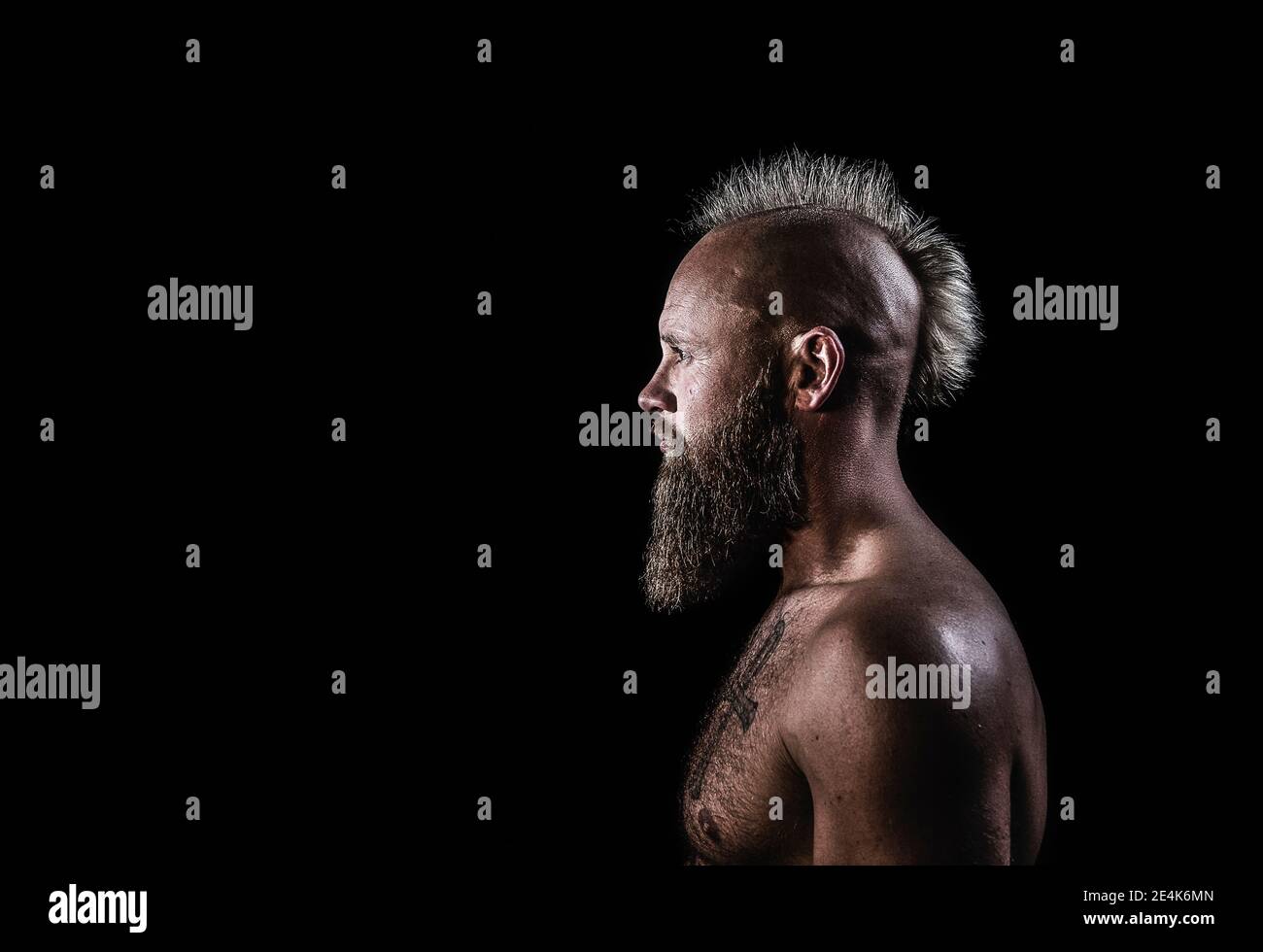 Male viking with mohawk hairstyle standing against black background ...
