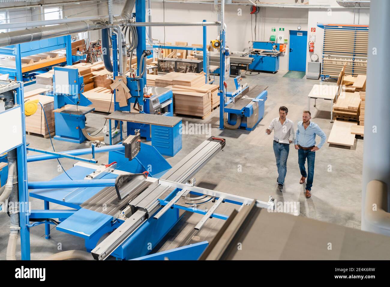 Two carpenters walking and talking in production hall Stock Photo - Alamy