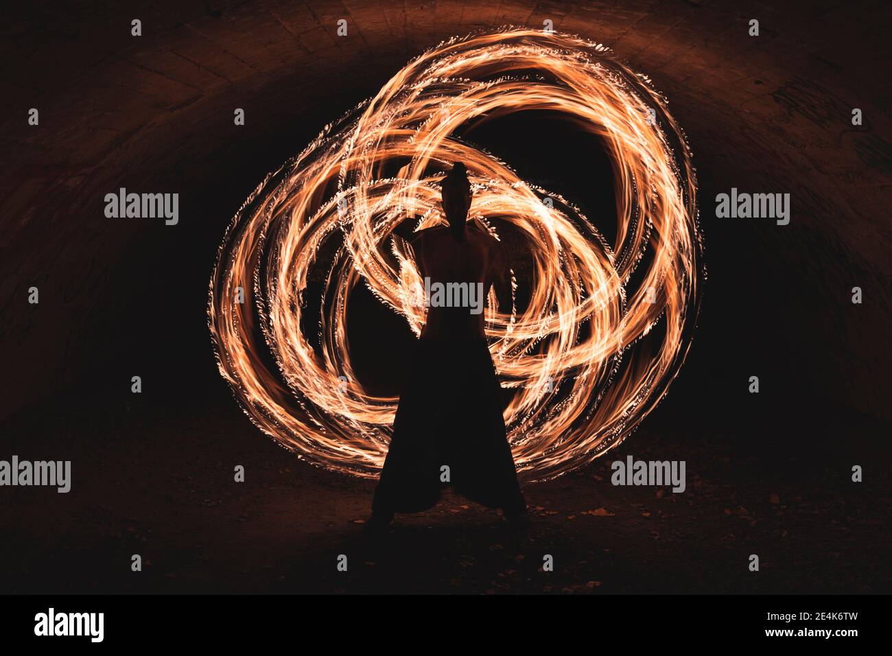 Young man performing fire ring skill in dark tunnel Stock Photo - Alamy