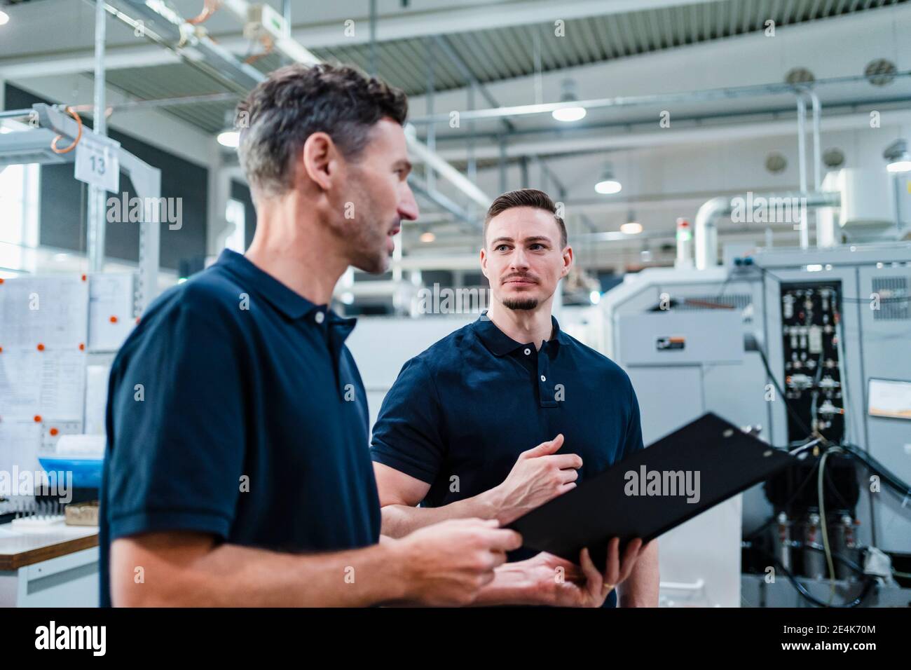 Male engineer looking at coworker while discussing in industry Stock ...