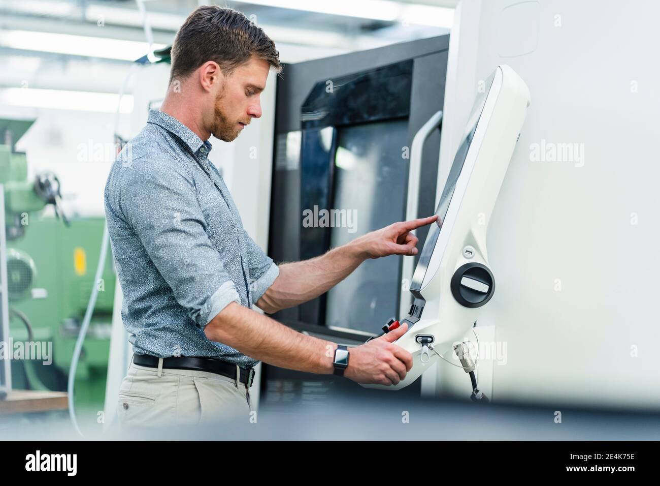 Male entrepreneur using machinery equipment while working in factory ...
