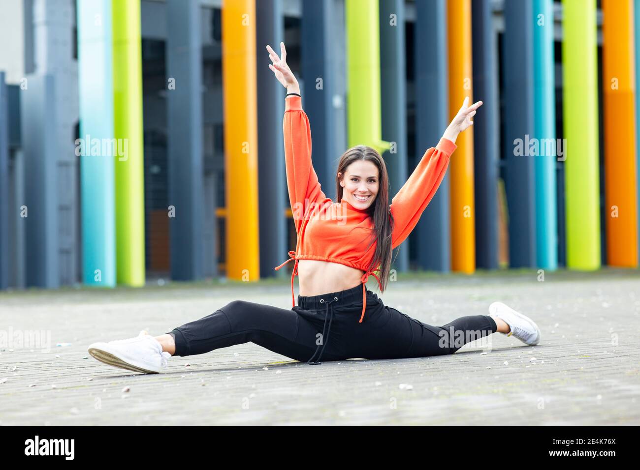 Portrait of beautiful brunette doing splits in front of colorful ...